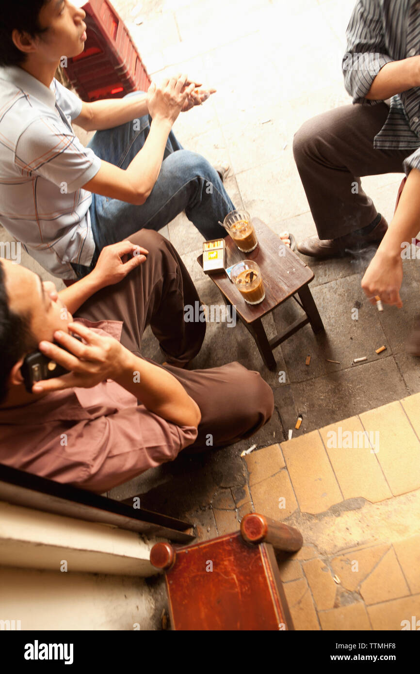 VIETNAM, Hanoi, friends smoke, drink coffee and talk on their phones at ...