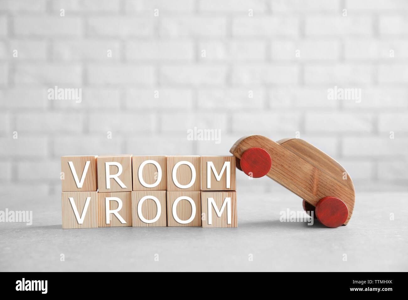 Cubes with words VROOM VROOM and toy car on brick wall background Stock ...