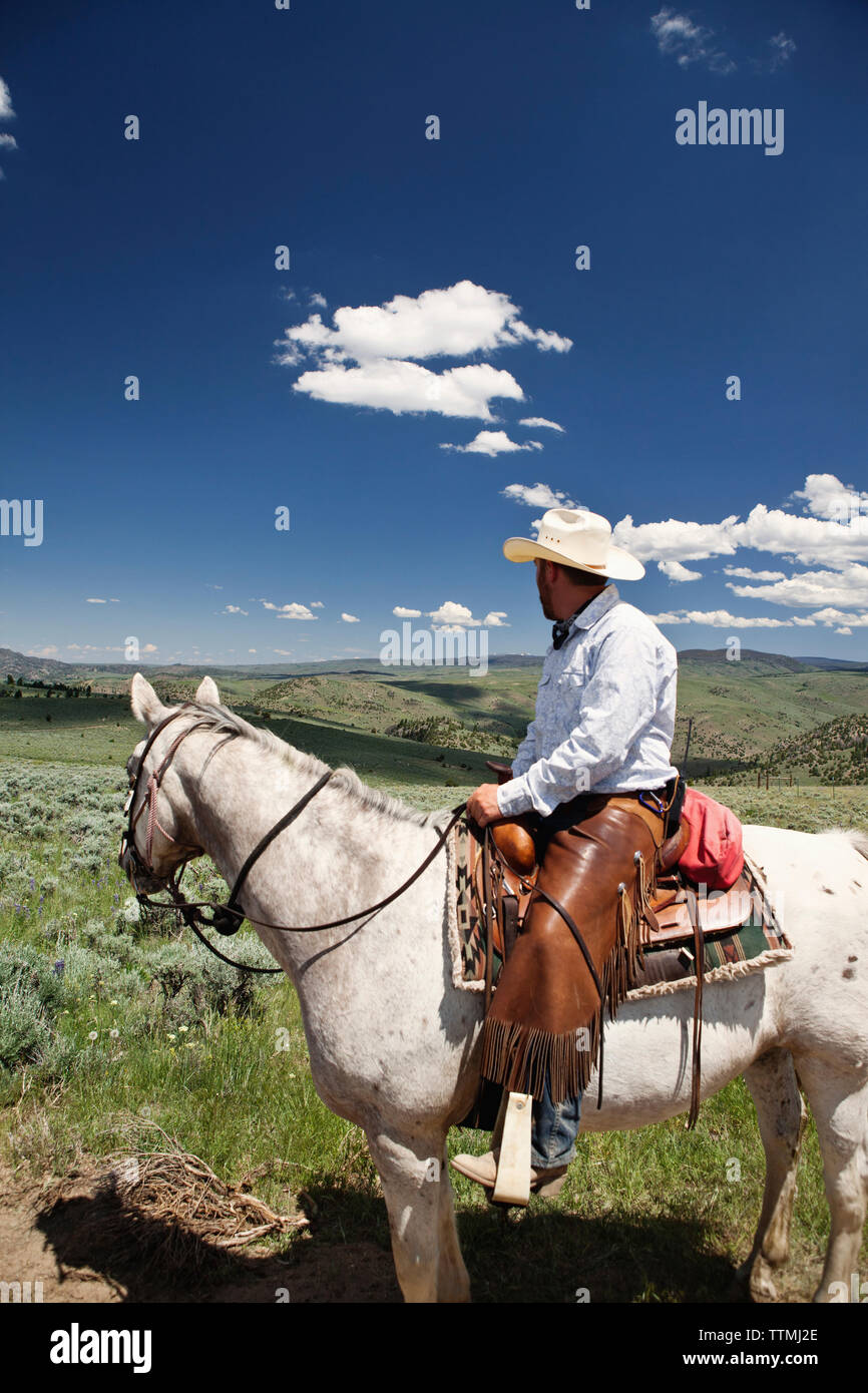 USA, Wyoming, Encampment, a cowboy sits on his horse and looks to the ...