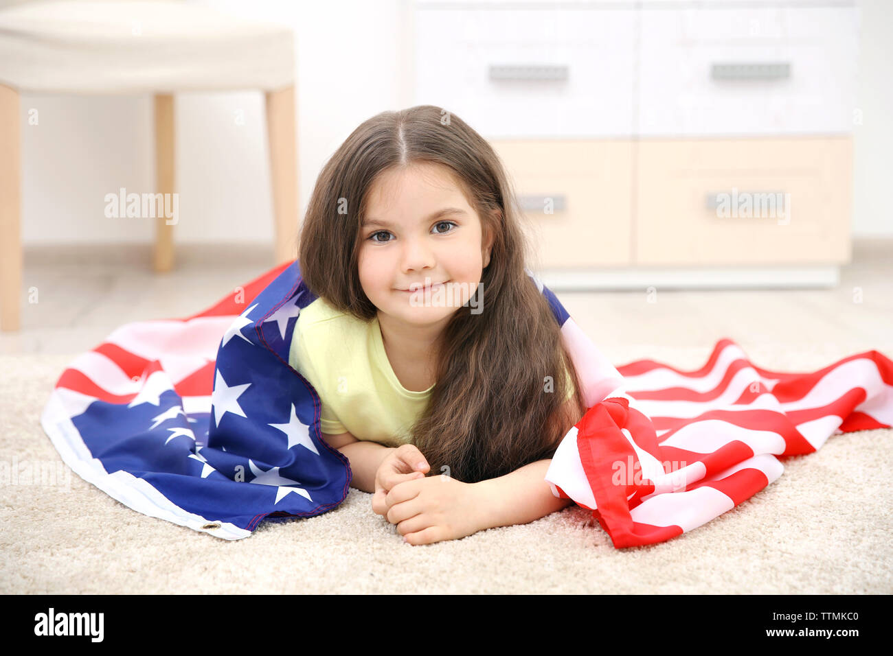 Cute little girl and American flag in room Stock Photo - Alamy