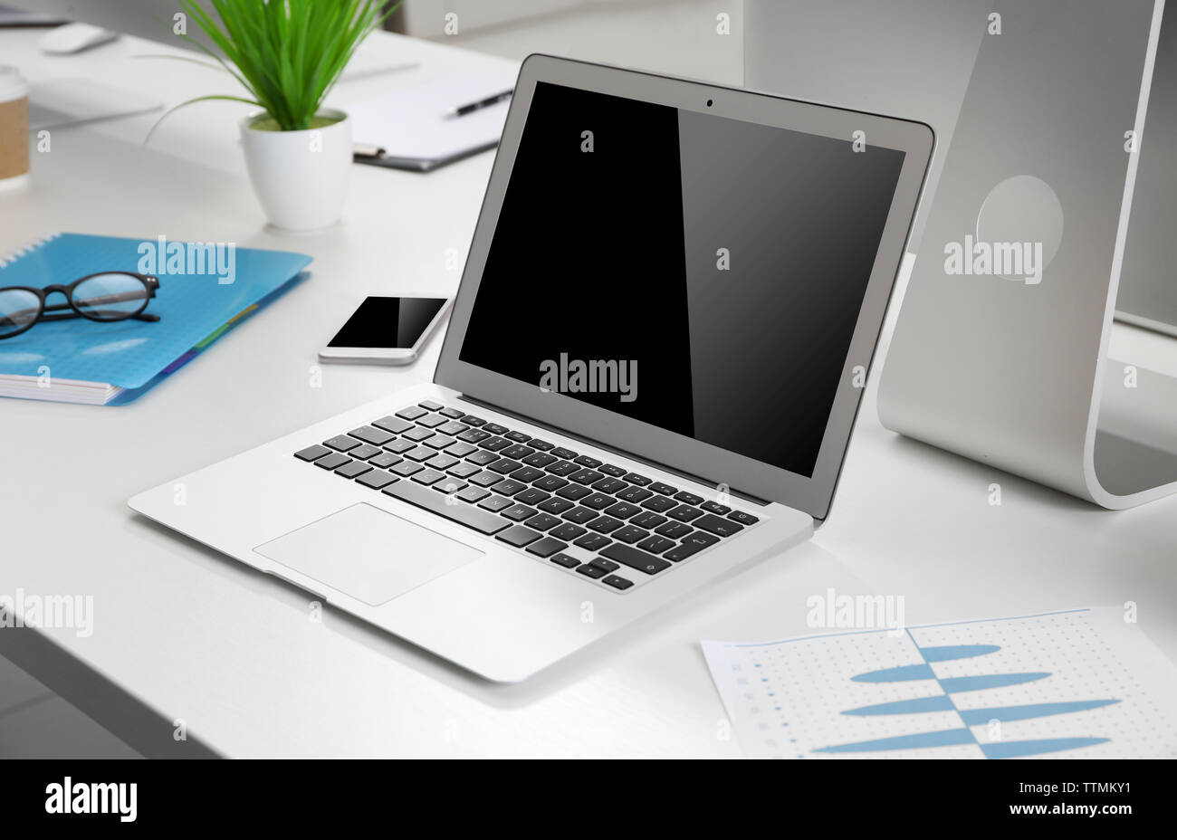 Laptop on white table Stock Photo - Alamy