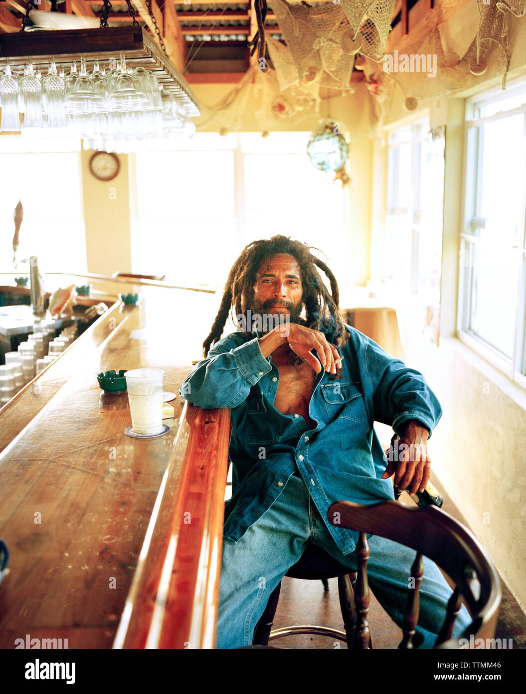 CAYMAN ISLANDS, Grand Cayman, portrait of man with dreadlocks sitting ...