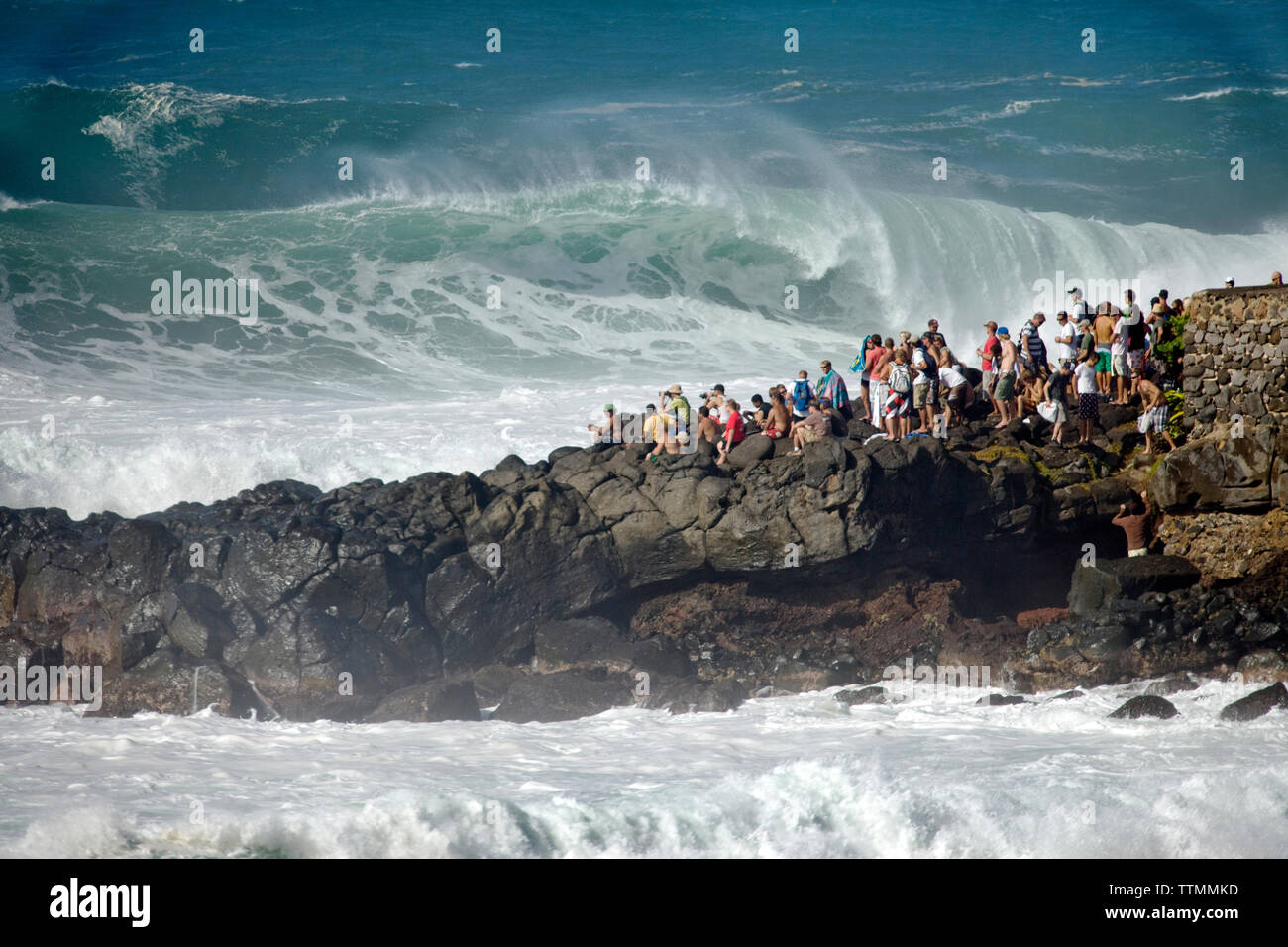 USA, Hawaii, Oahu, group of people watching surfing at Waimea Bay Stock ...