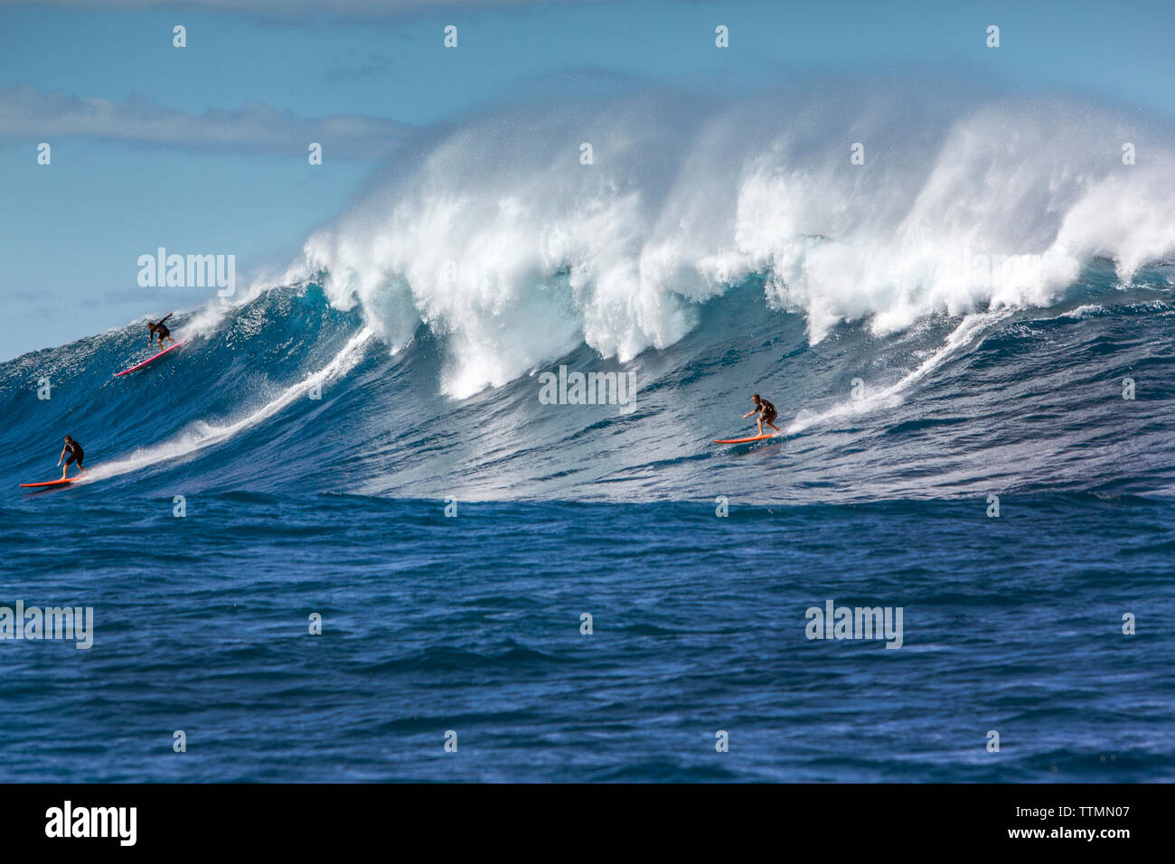 USA, HAWAII, Maui, Jaws, big wave surfers taking off on a wave at Peahi ...