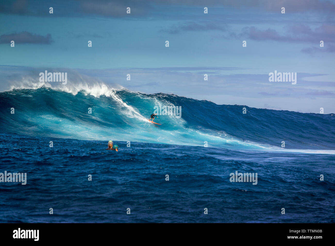 USA, HAWAII, Maui, Jaws, big wave surfers taking off on a wave at Peahi ...
