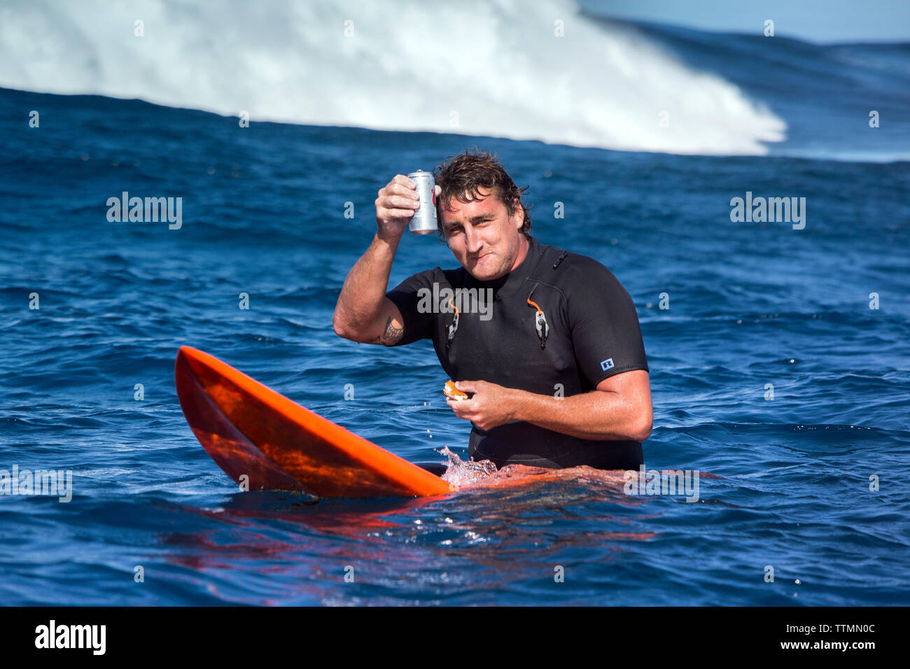 USA, HAWAII, Maui, Jaws, big wave surfer enjoying a beer in the water ...