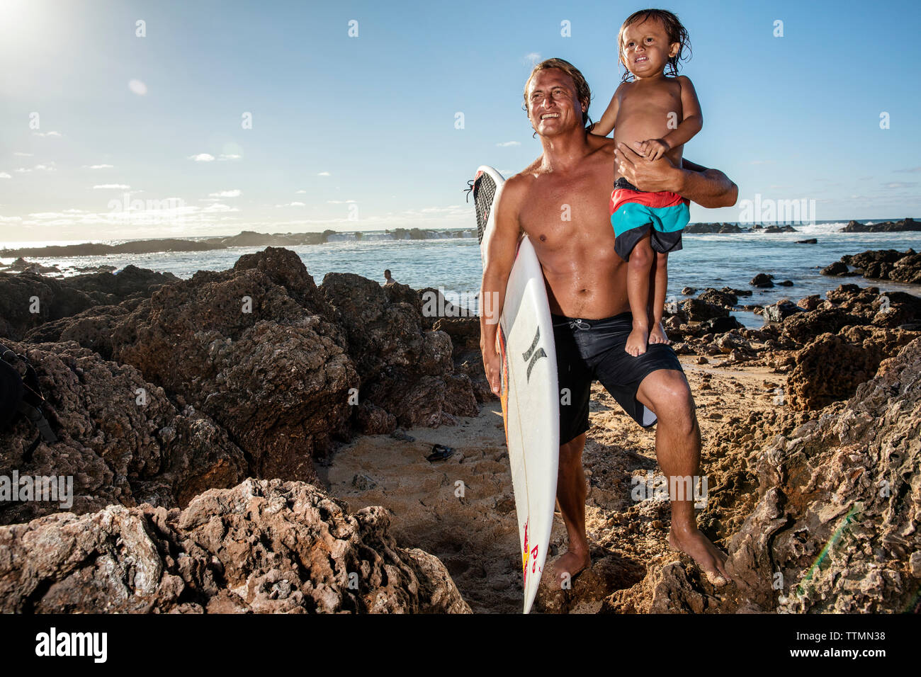 HAWAII, Oahu, North Shore, a man teaching his young son to surf in ...