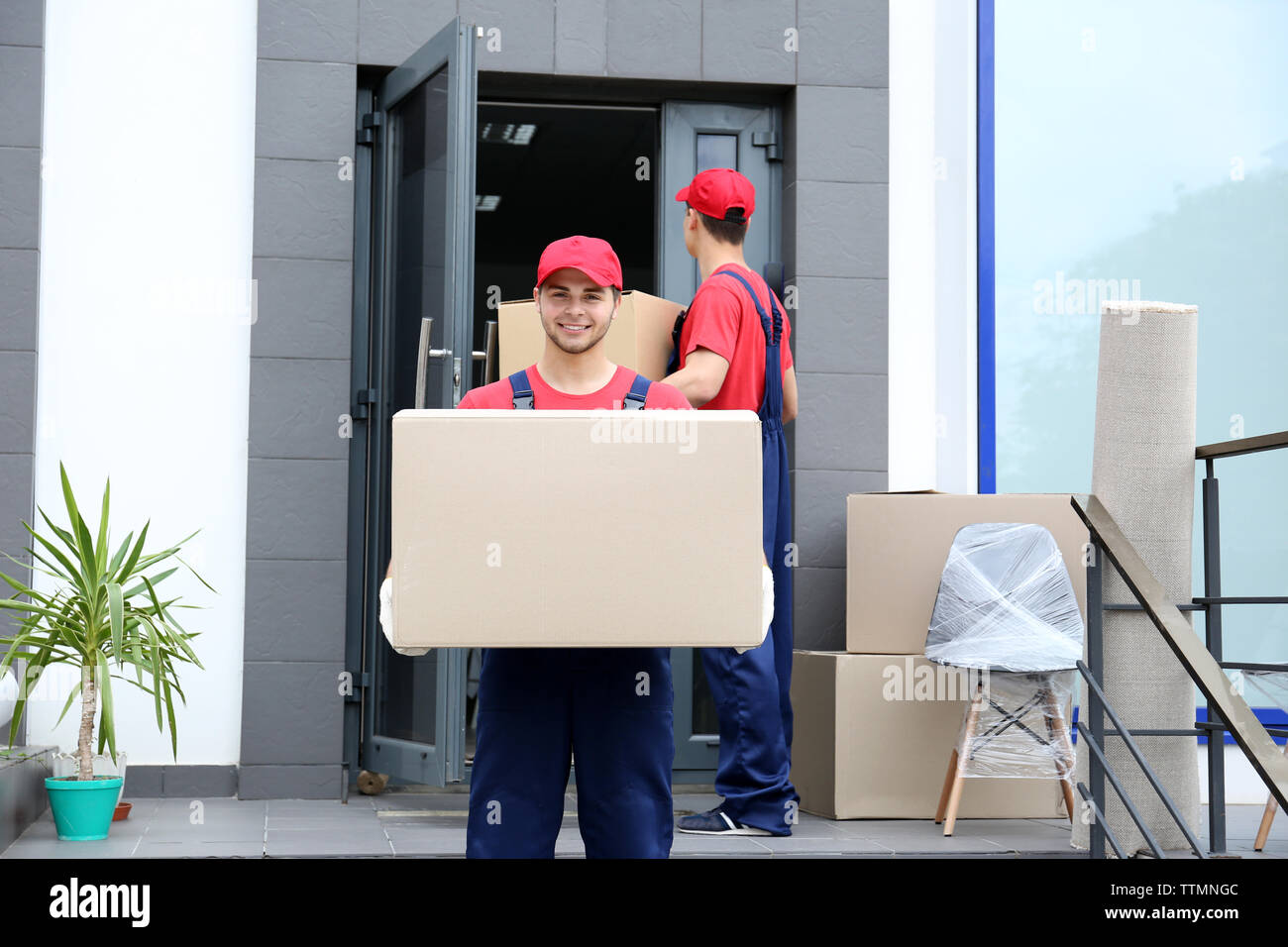 Two male workers with heavy boxes Stock Photo - Alamy