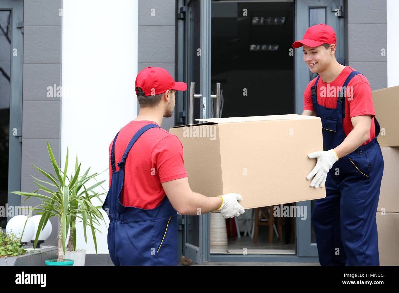 Two male workers with heavy boxes Stock Photo - Alamy