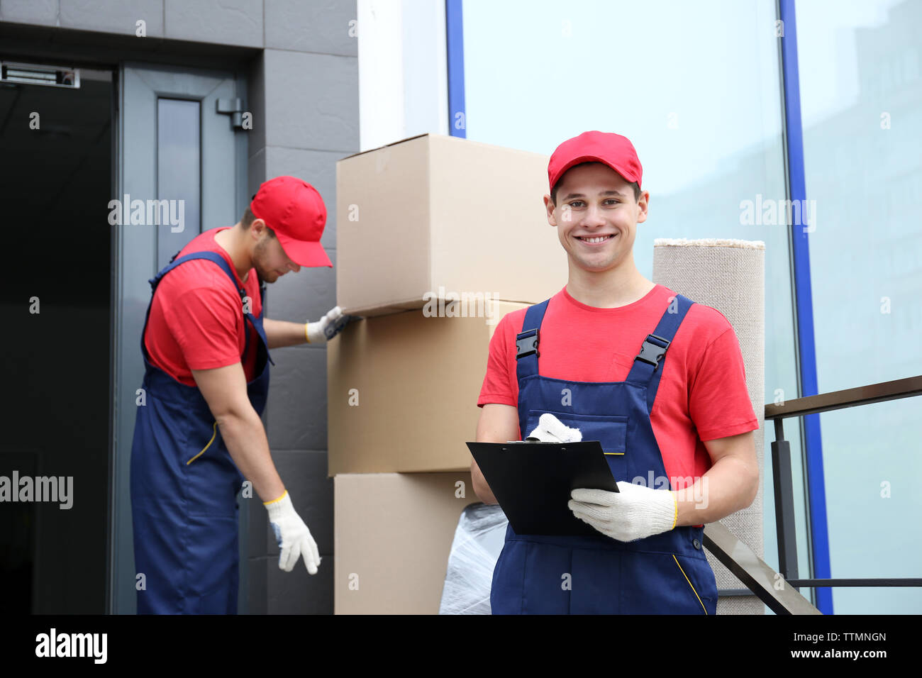 Two male workers with heavy boxes Stock Photo - Alamy