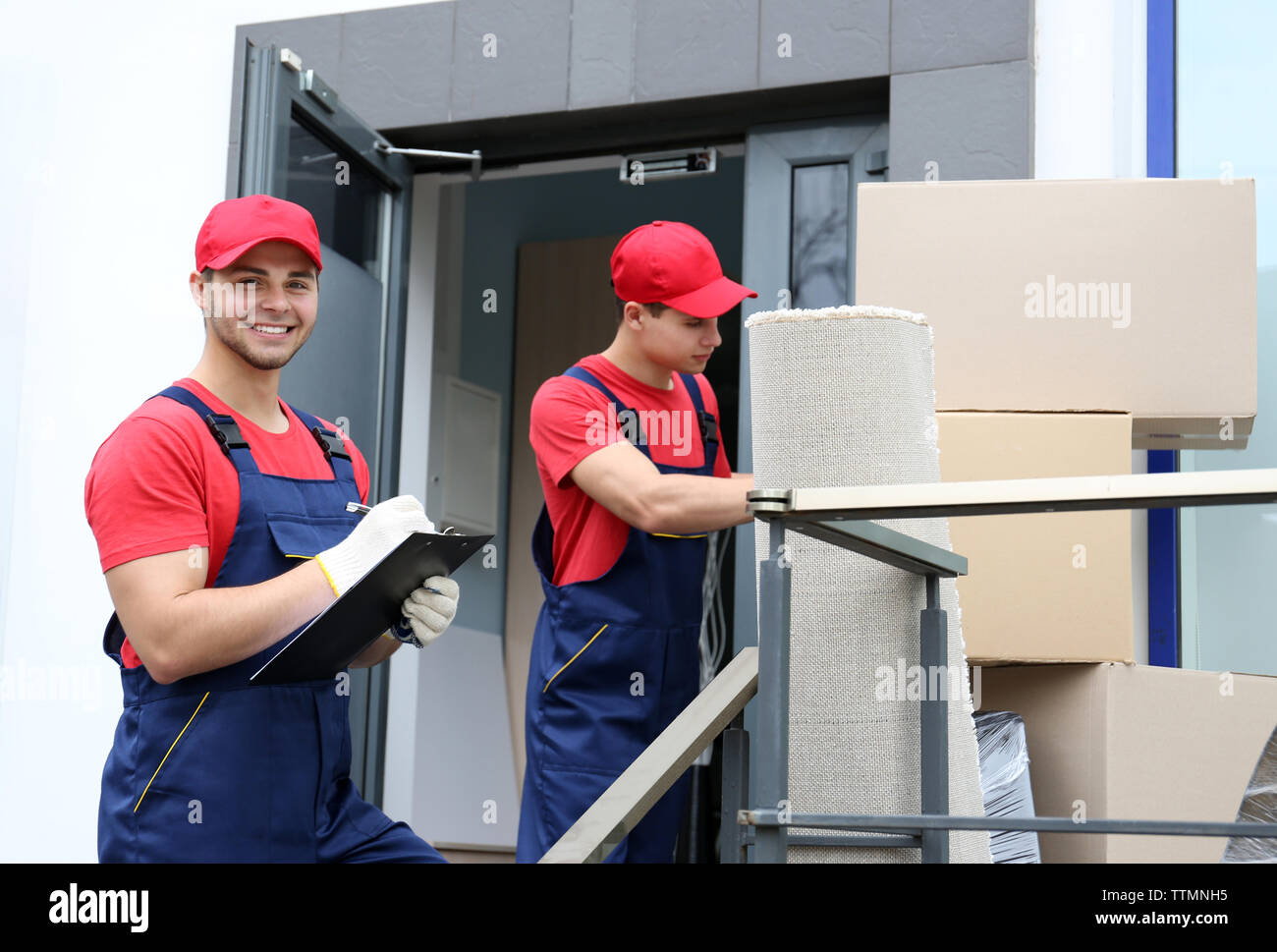 Two male workers with heavy boxes Stock Photo - Alamy