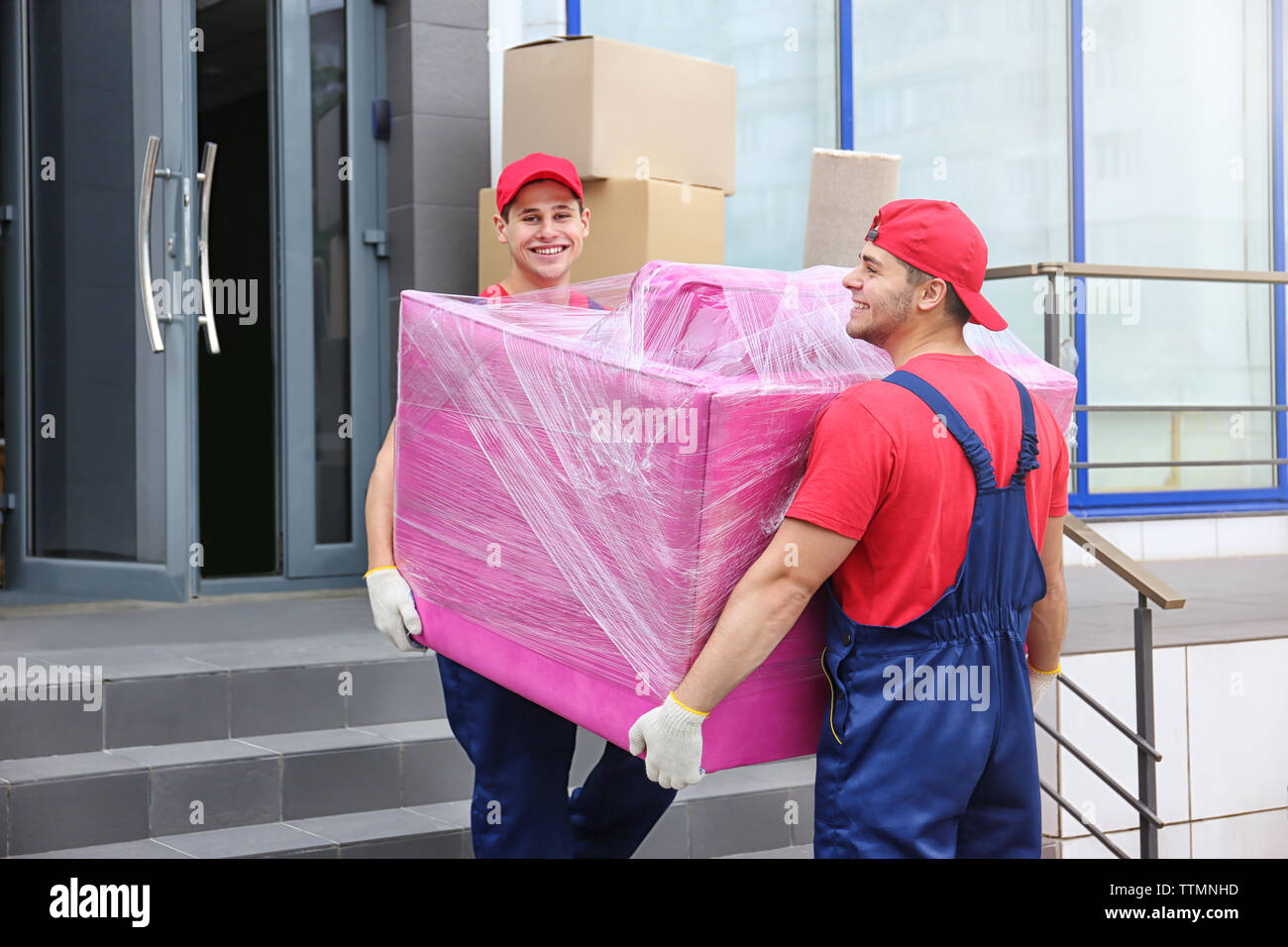 Two male workers with pink armchair Stock Photo - Alamy