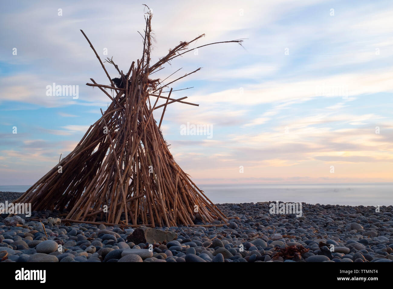 Bamboo Teepee on rocky beach Stock Photo - Alamy