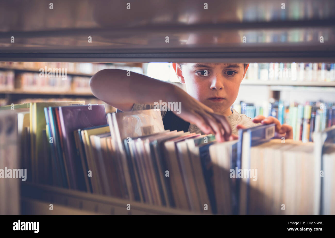 Serious boy searching for book from shelf at library Stock Photo - Alamy