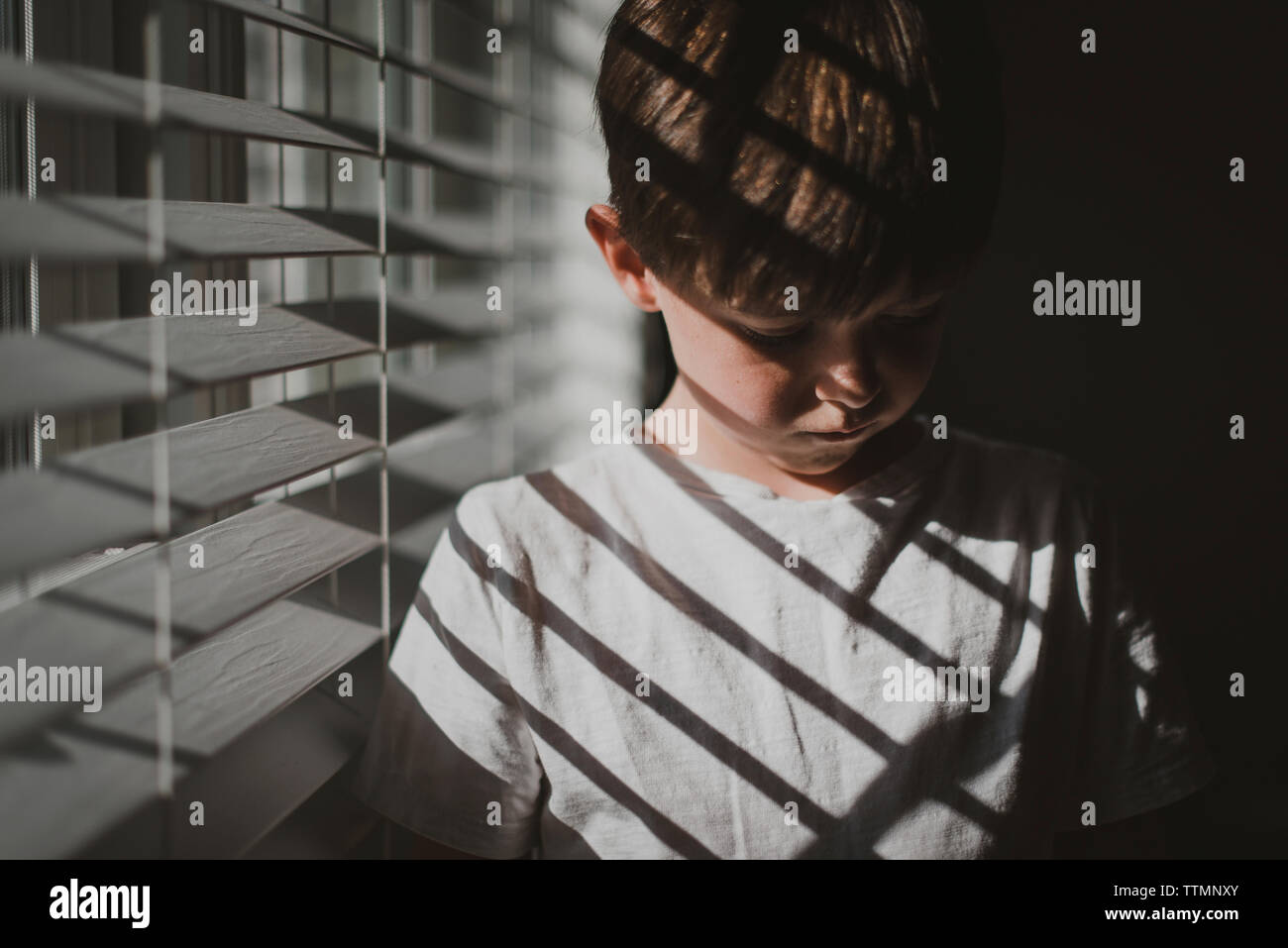 Boy standing by window at home Stock Photo - Alamy