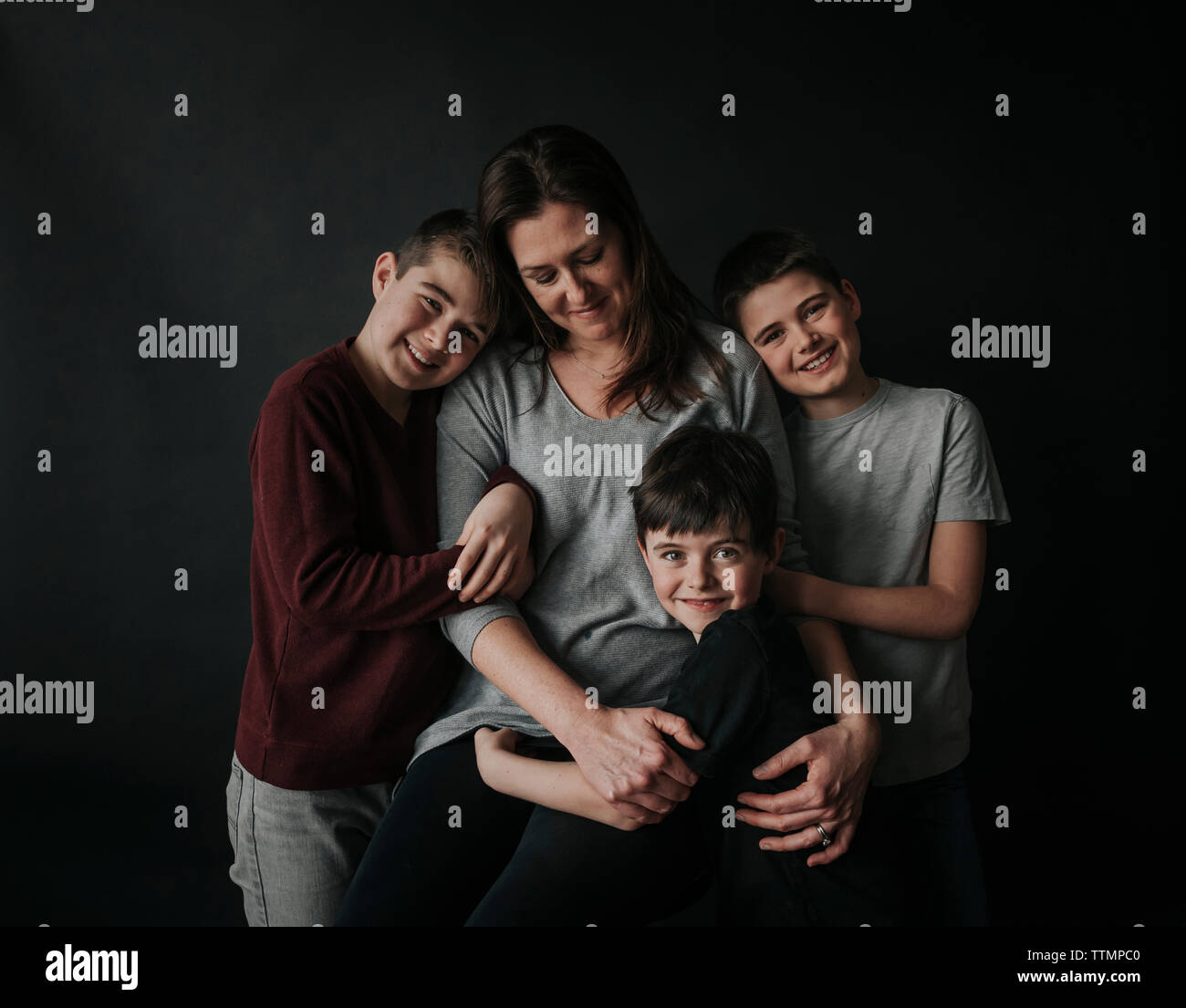 Portrait of sons with mother standing against black background Stock ...