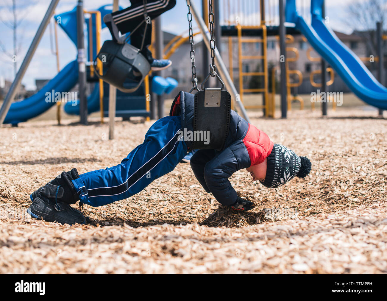 Side view of boy swinging at playground Stock Photo - Alamy