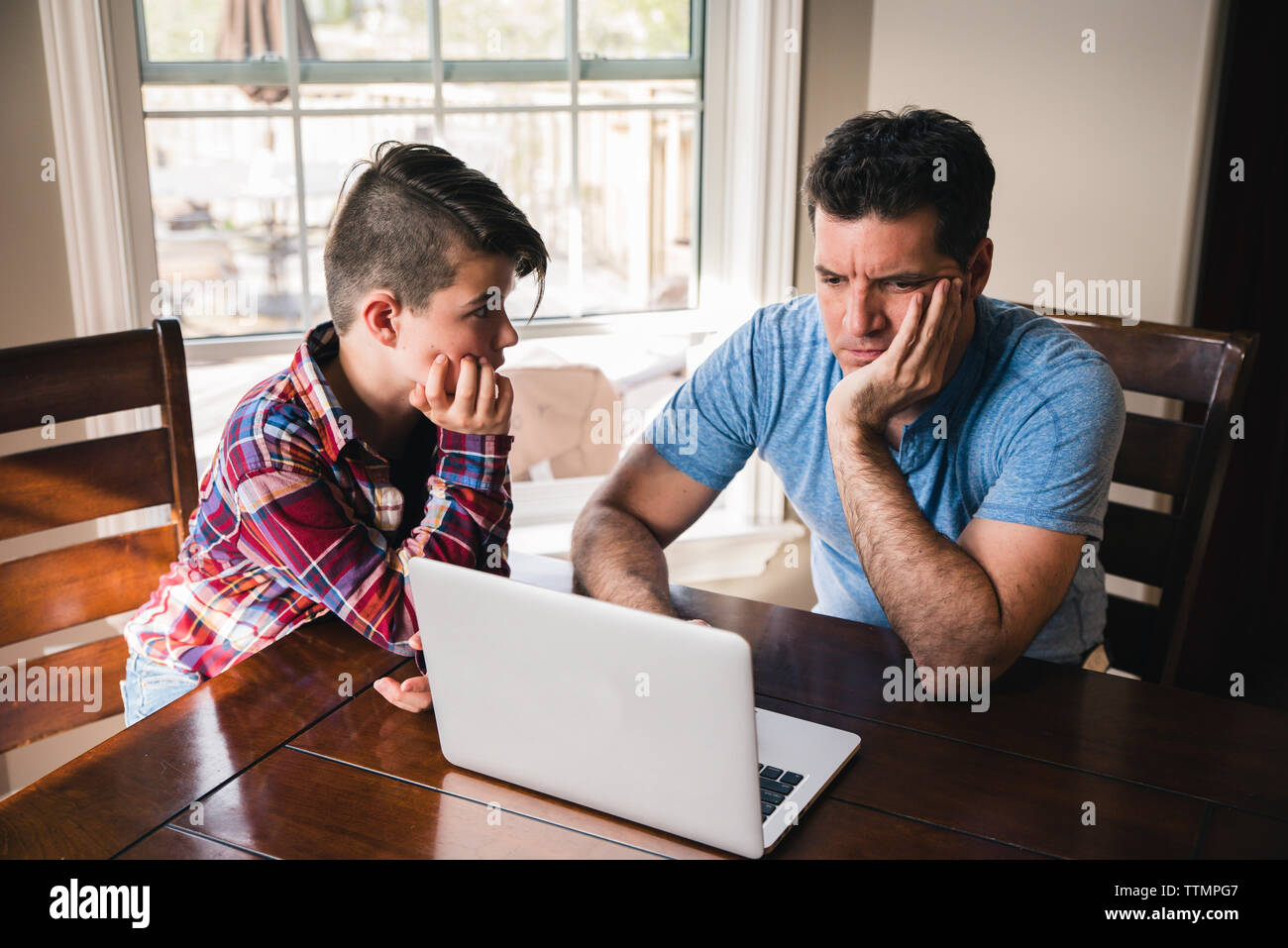 Son looking at stressed father using laptop computer at home Stock ...
