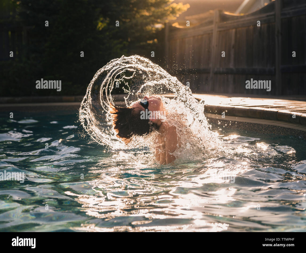 Side view of boy tossing wet hair in swimming pool during sunset Stock ...