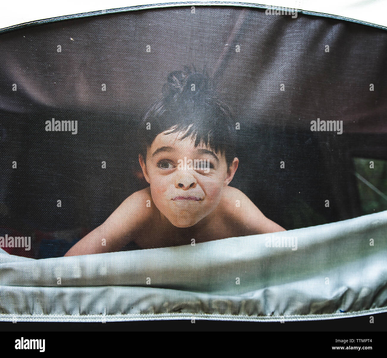 Boy making face while looking through tent Stock Photo - Alamy