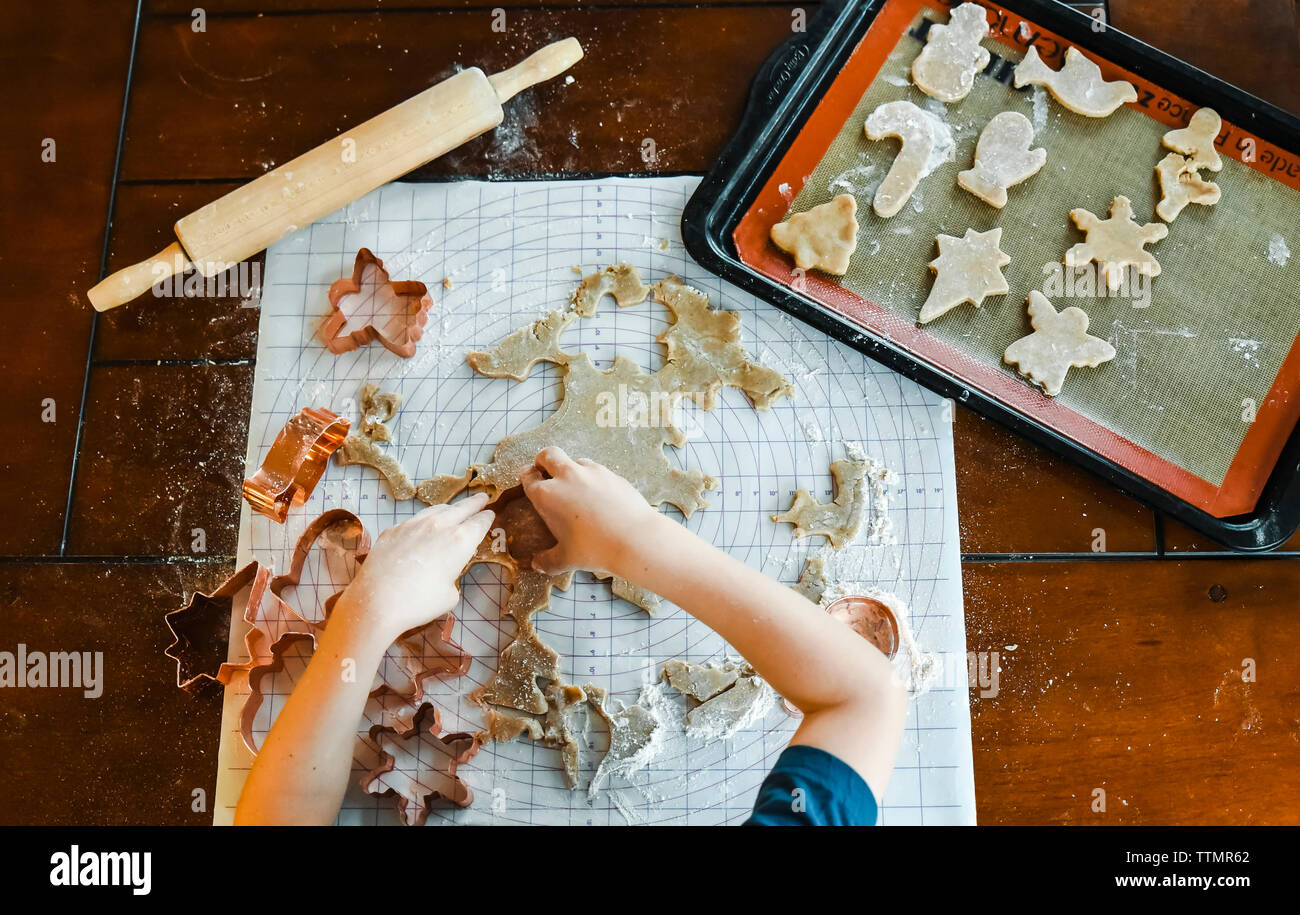 Overhead shot of child's hands making cookies using cookie cutters ...