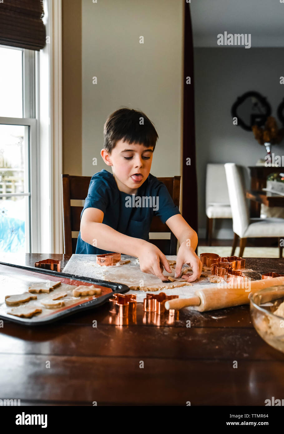 Young boy making cookies with cookie cutters at the table Stock Photo ...