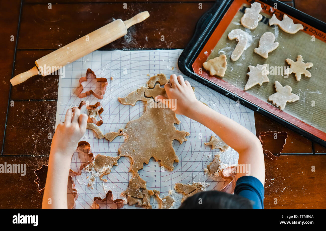 Overhead shot of child's hands making cookies using cookie cutters ...