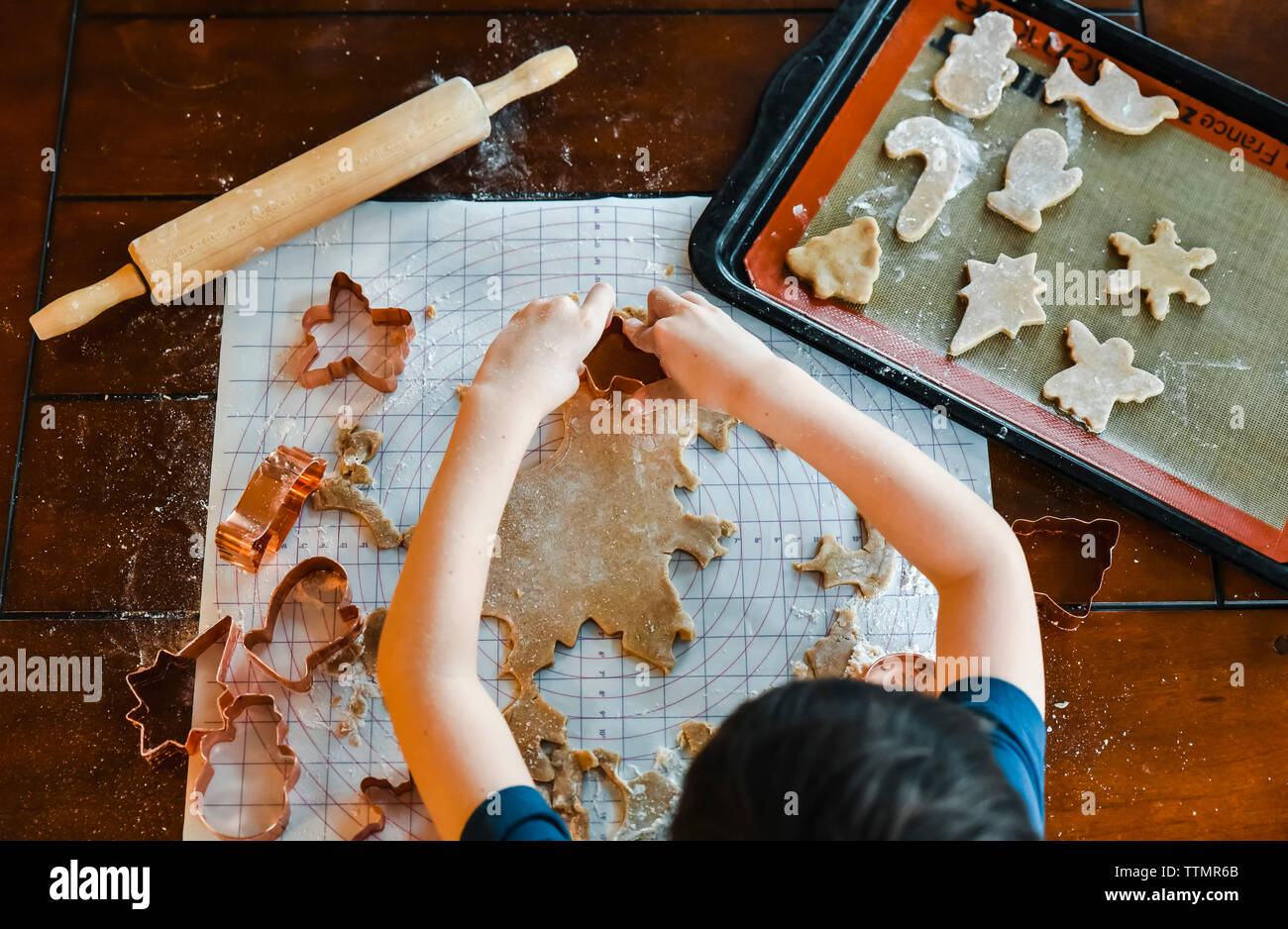 Overhead shot of child's hands making cookies using cookie cutters ...