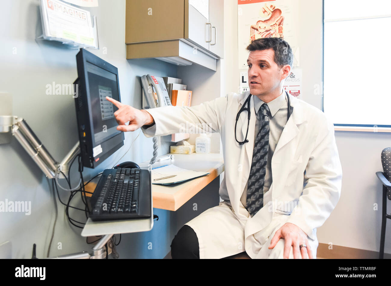 Doctor in white coat pointing at computer screen in a clinic room Stock ...