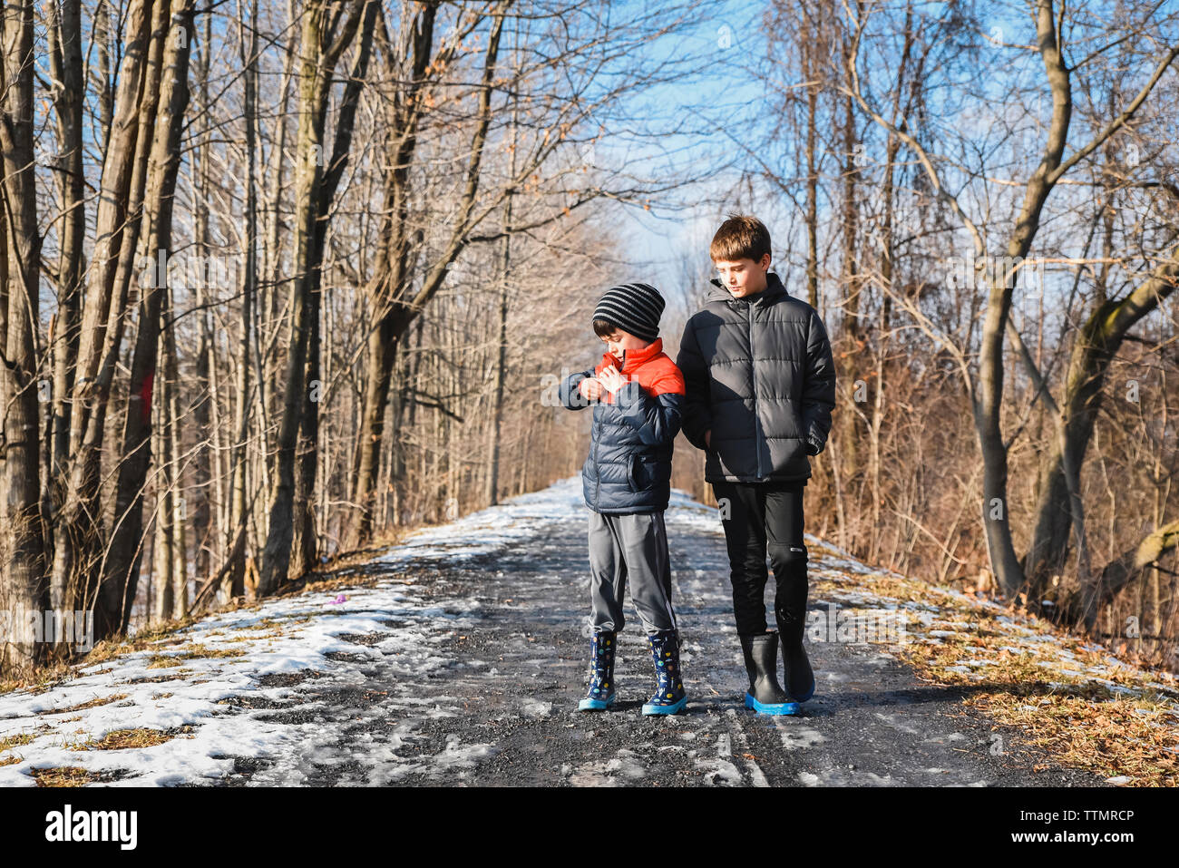 Two boys walking together on a snowy trail in winter Stock Photo - Alamy