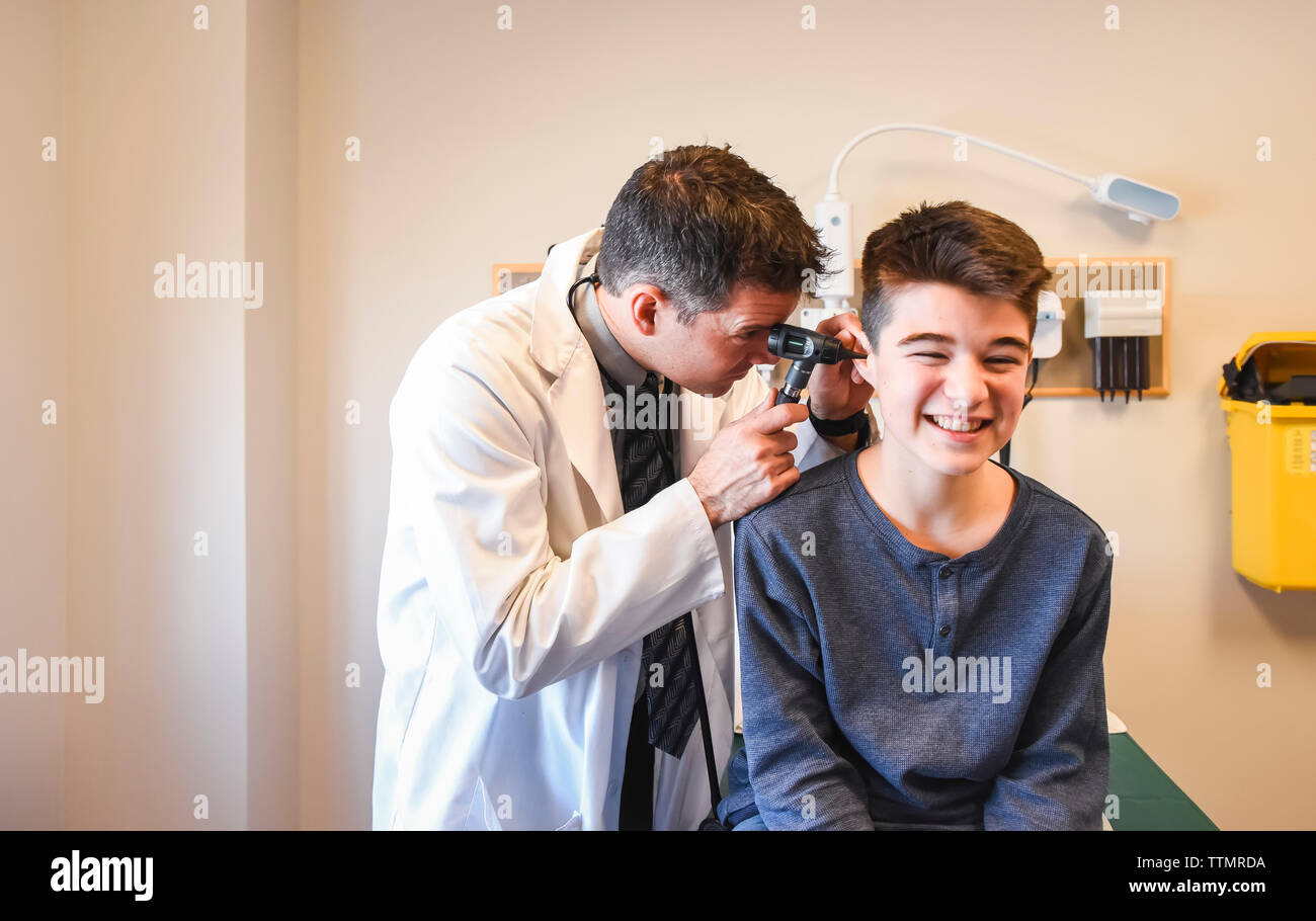 Doctor looking into ear of teenage patient in an examination room Stock ...