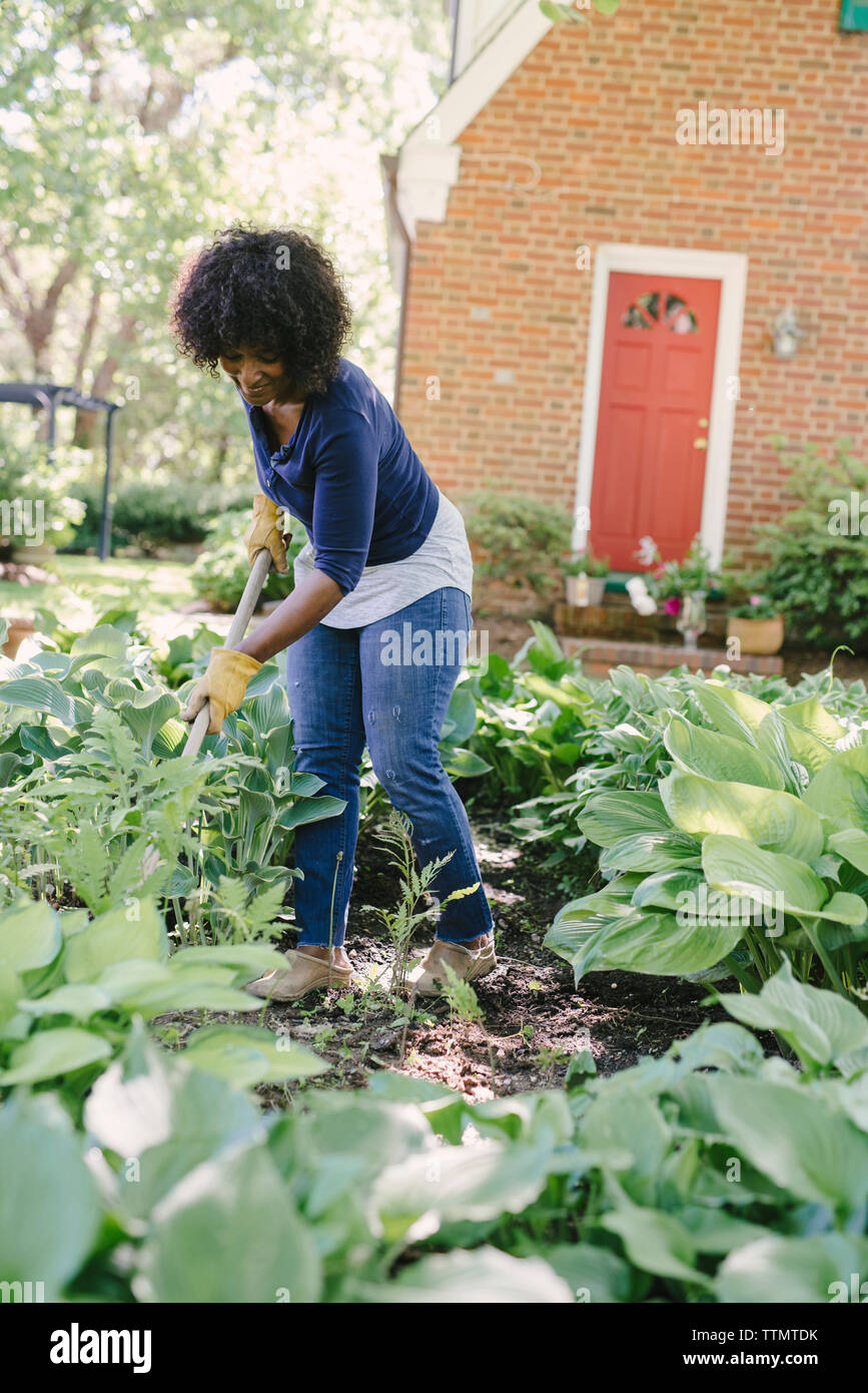 Woman using gardening fork while working in garden Stock Photo - Alamy