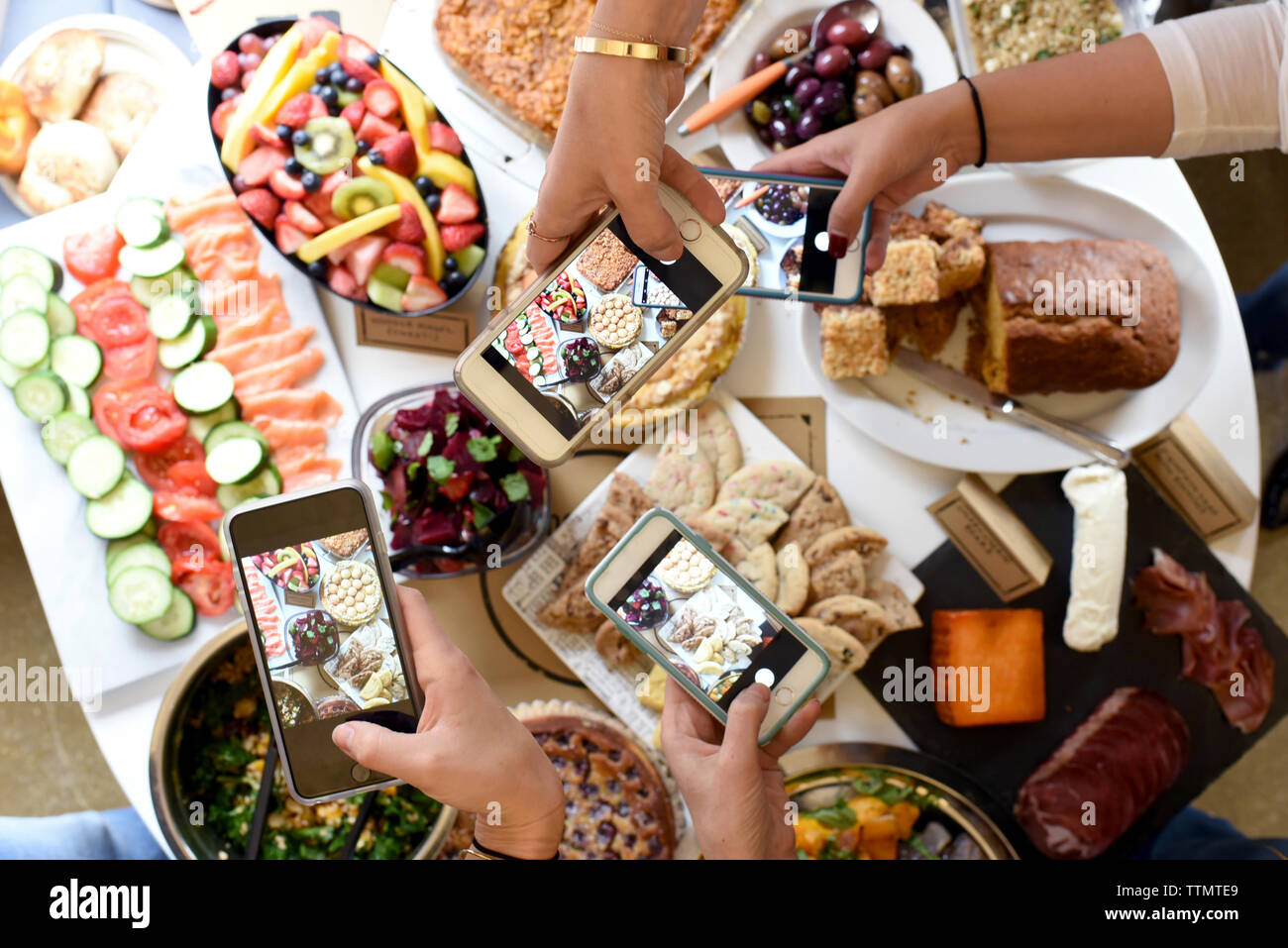 Cropped hands of people photographing food through mobile phones on ...