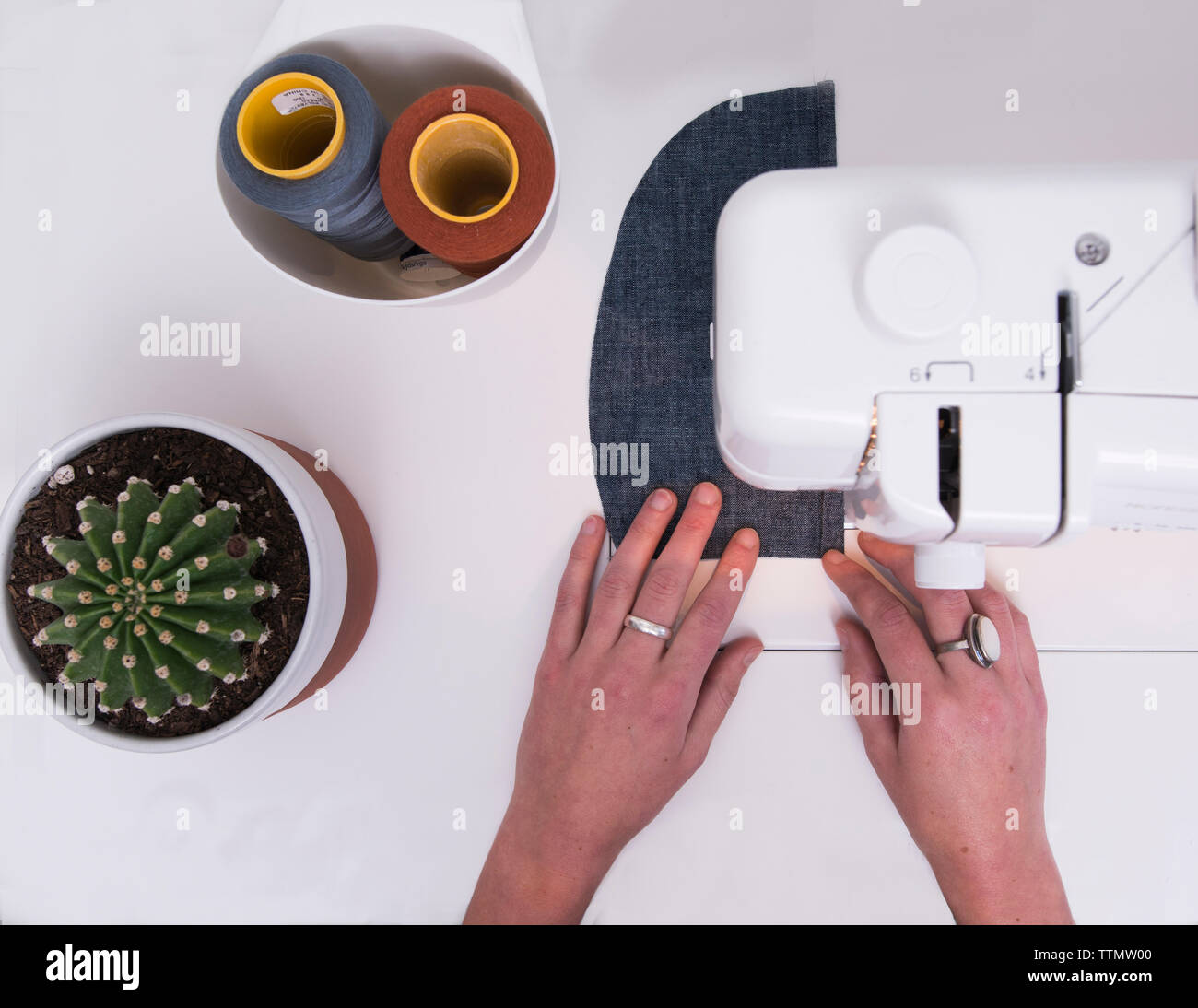 Overhead view of female tailor using sewing machine at table in ...