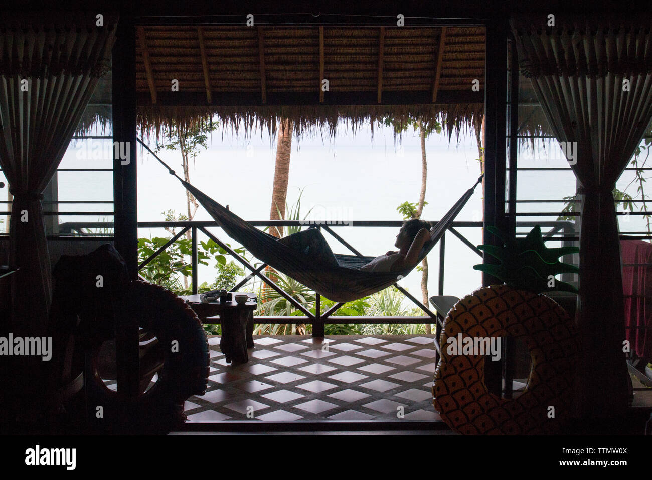 Side view of woman relaxing on hammock in cottage against sea Stock ...