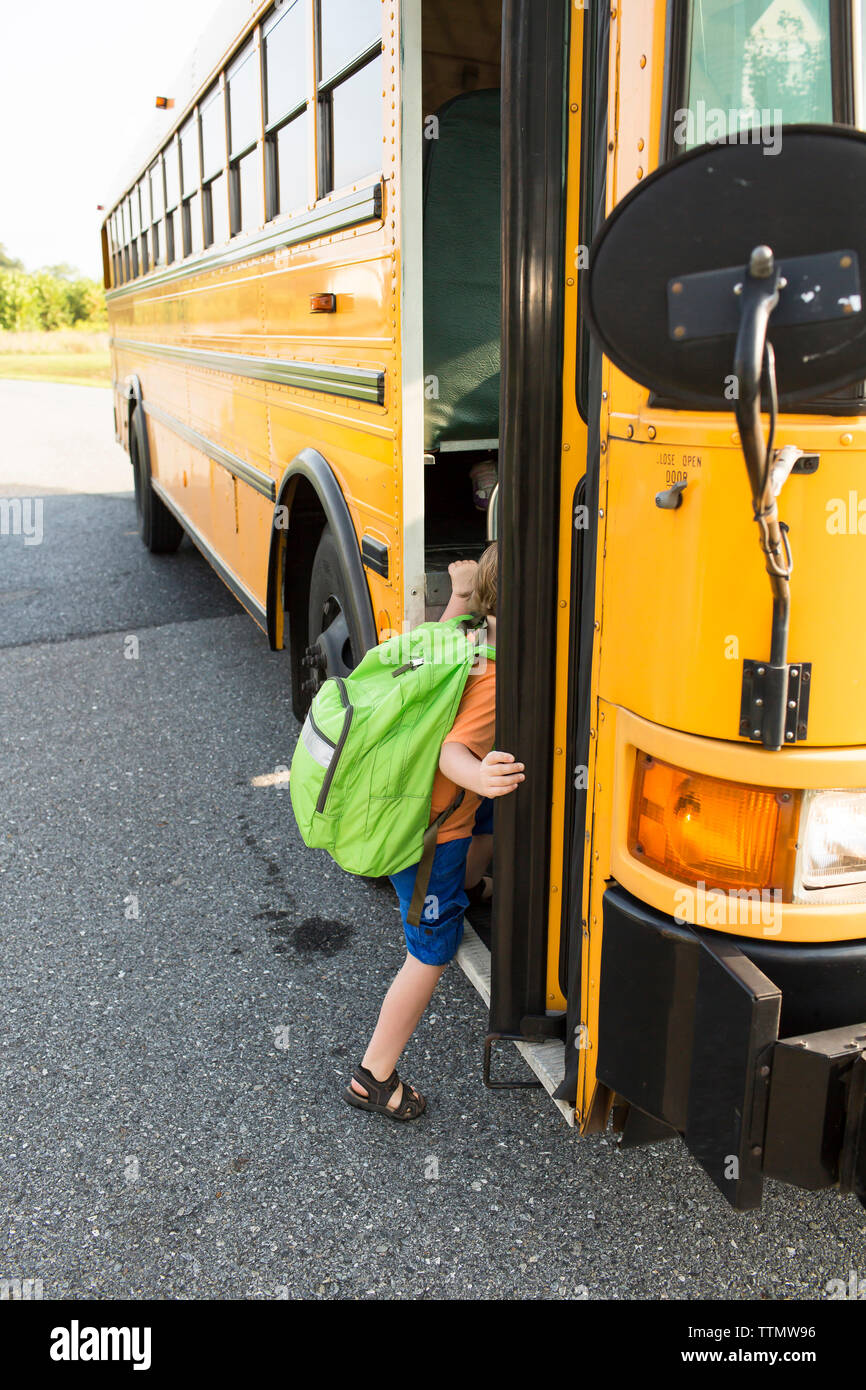 Boy getting in school bus on street Stock Photo - Alamy