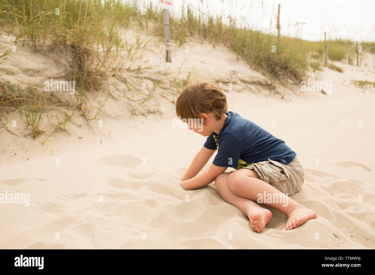 Boy playing with sand at beach Stock Photo - Alamy