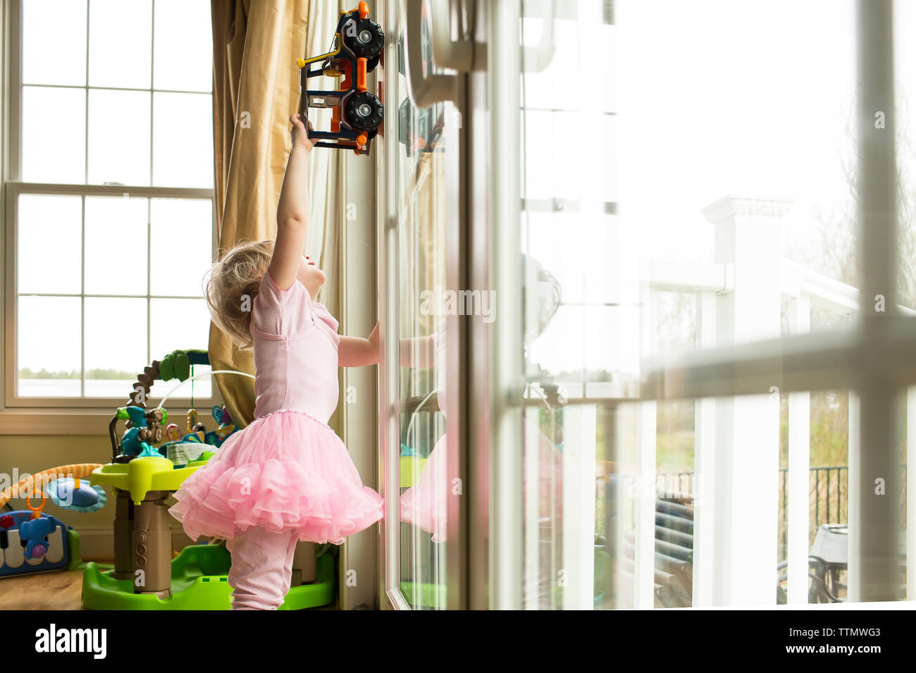 Girl playing with toy car on window at home Stock Photo - Alamy
