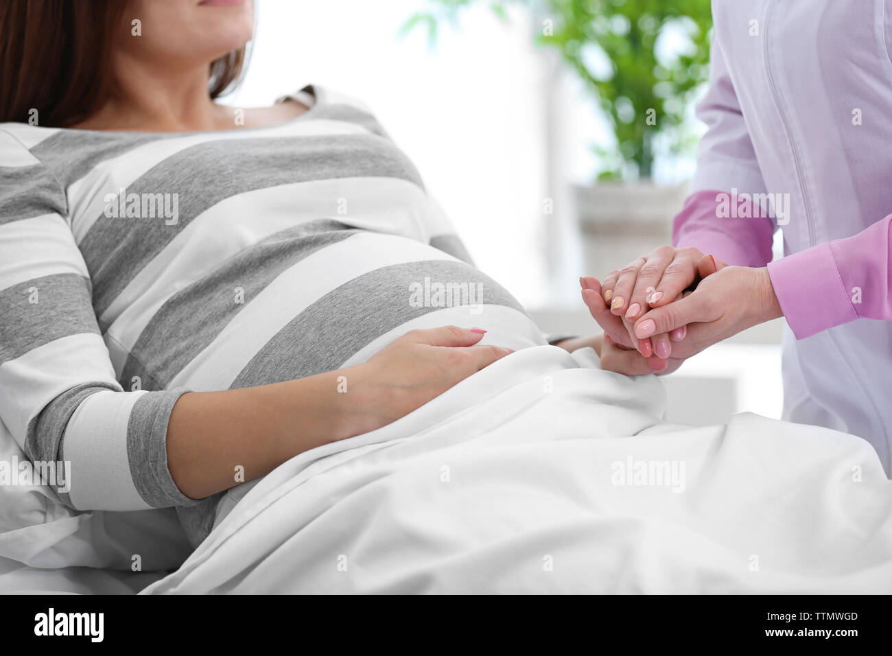 Doctor holding pregnant woman's hand Stock Photo - Alamy