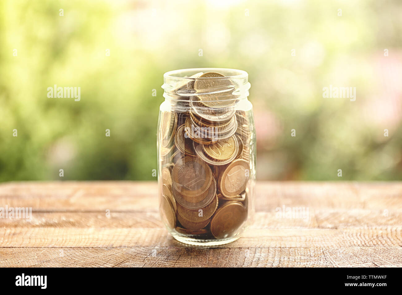 Coins in jar on nature background Stock Photo - Alamy