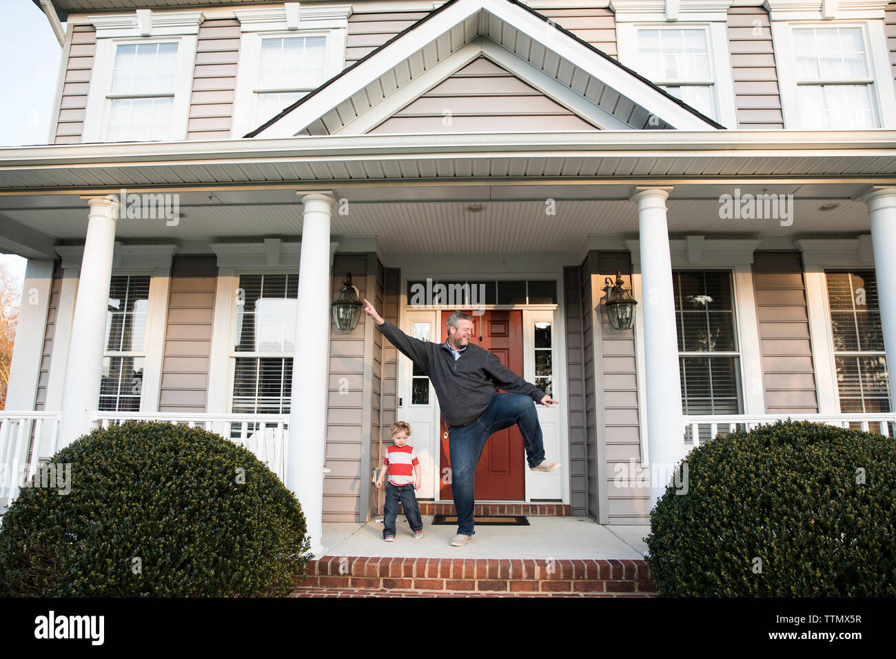 Dad Does Silly Pose Standing on Front Porch of House with Toddler Stock ...