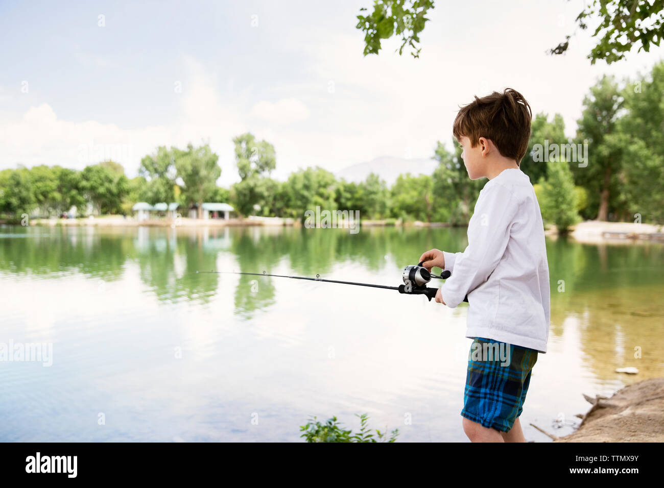 Side view of boy fishing in lake Stock Photo - Alamy