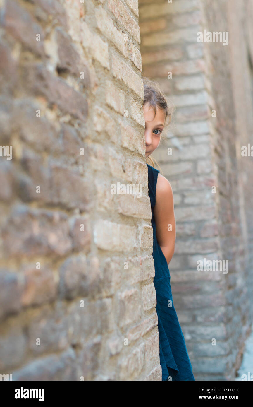 Portrait of girl hiding by wall Stock Photo - Alamy