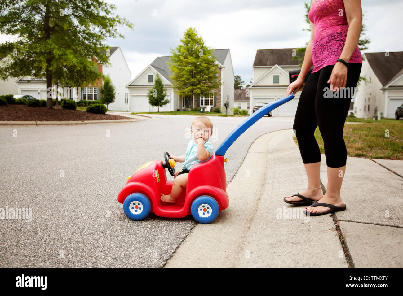 Mother pushing son in toy car Stock Photo - Alamy