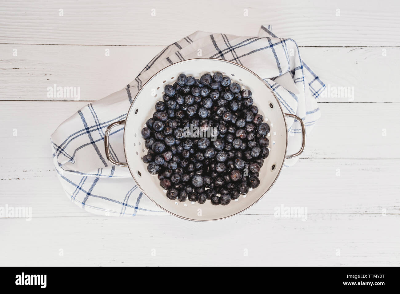 High angle view of blueberries in plate with napkin on wooden table ...