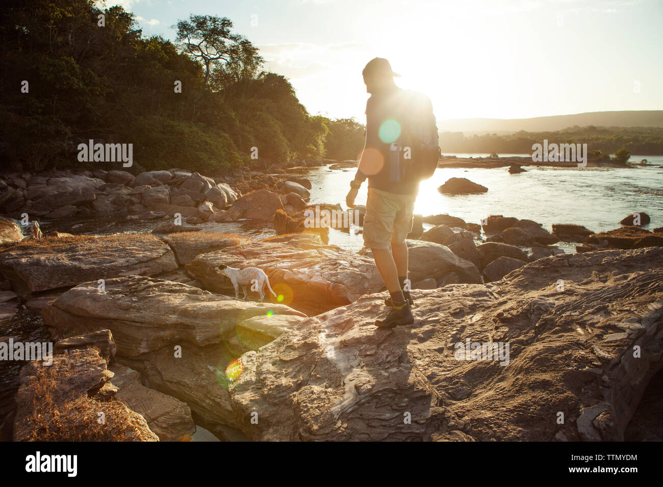 Side view of male hiker walking on rocky lakeshore during sunset Stock ...