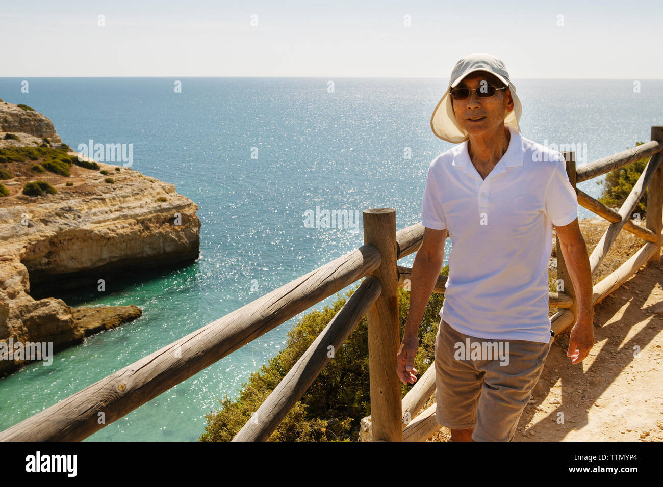 Senior man walking on cliff by railing against sea Stock Photo - Alamy