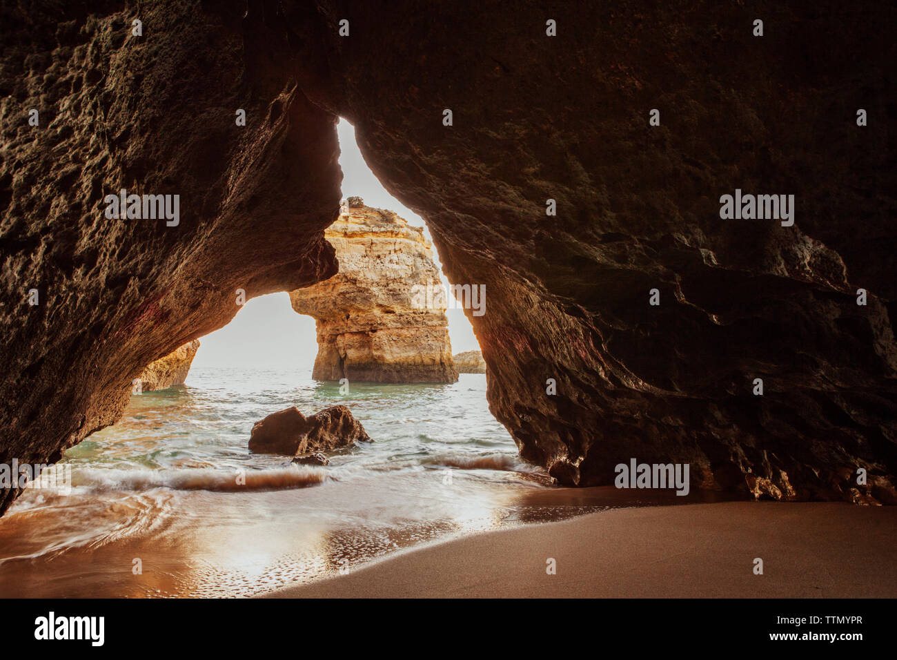 Natural arch in sea seen through cave Stock Photo - Alamy