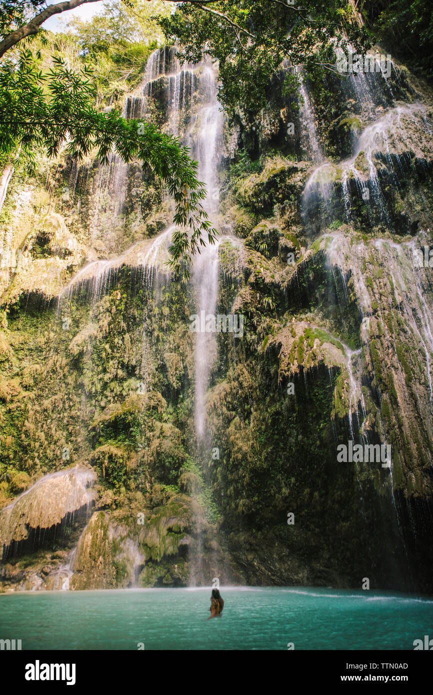 Woman swimming in river by waterfall at forest Stock Photo - Alamy