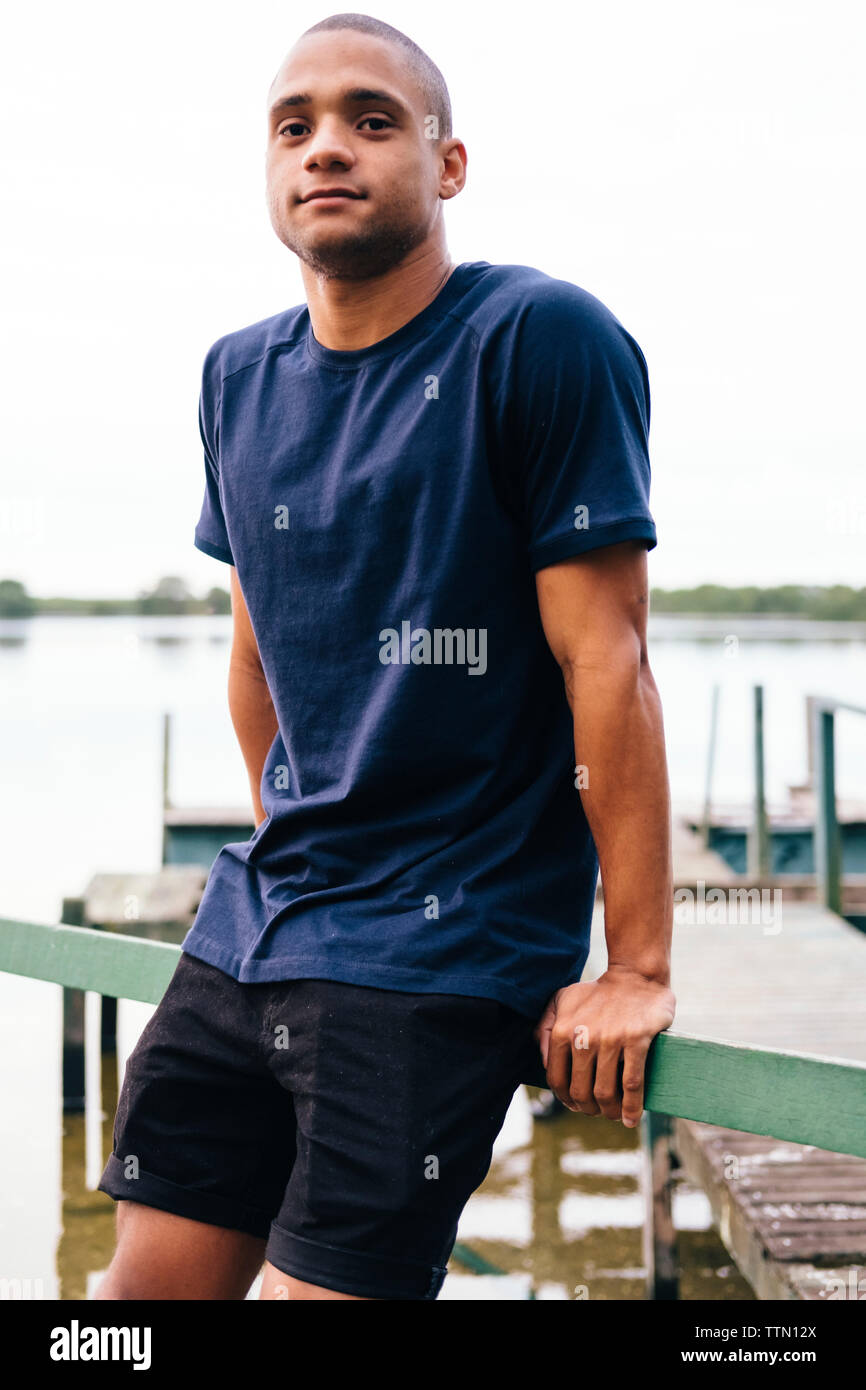 Portrait of young man leaning on railing against lake Stock Photo - Alamy